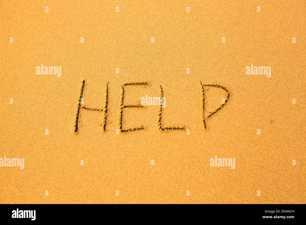 Help - written in sand on beach texture Stock Photo - Alamy