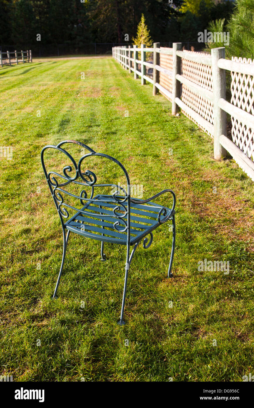 Chair in grass by fence Stock Photo - Alamy
