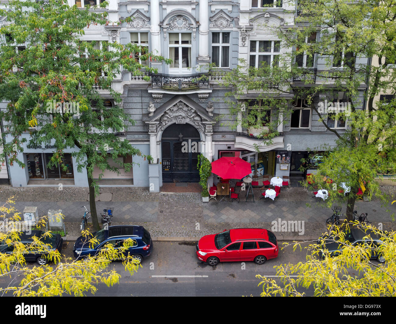 Elegant apartment building with classical facade, red umbrella, red car ...