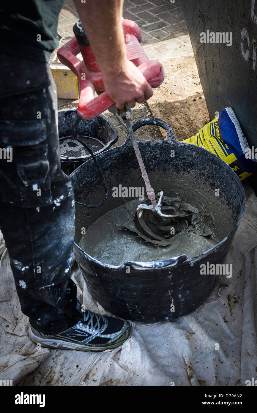 A workman using a power tool to mix concrete render in a tub Stock ...