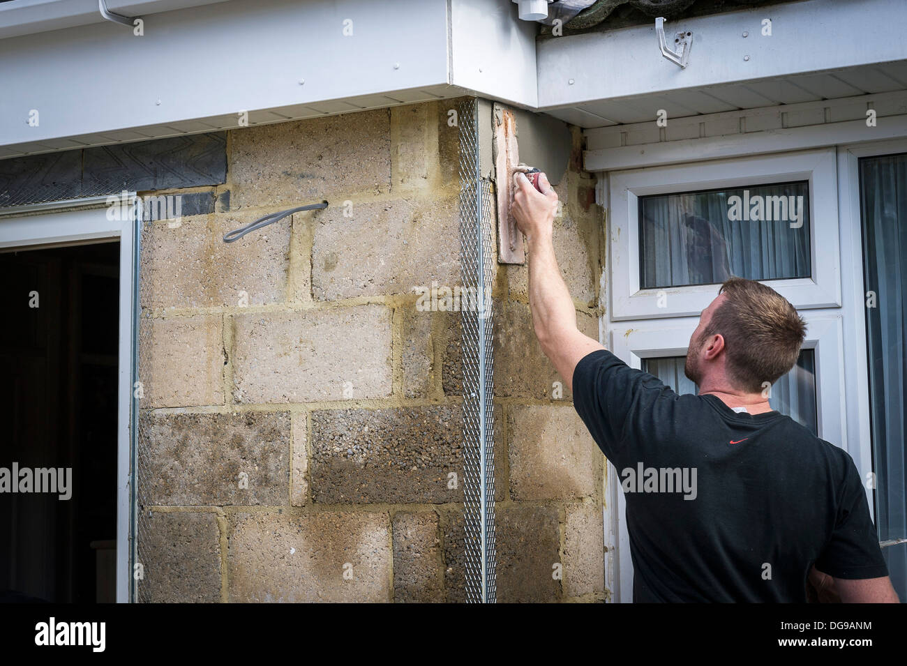 A workman rendering an exterior wall of a house Stock Photo - Alamy