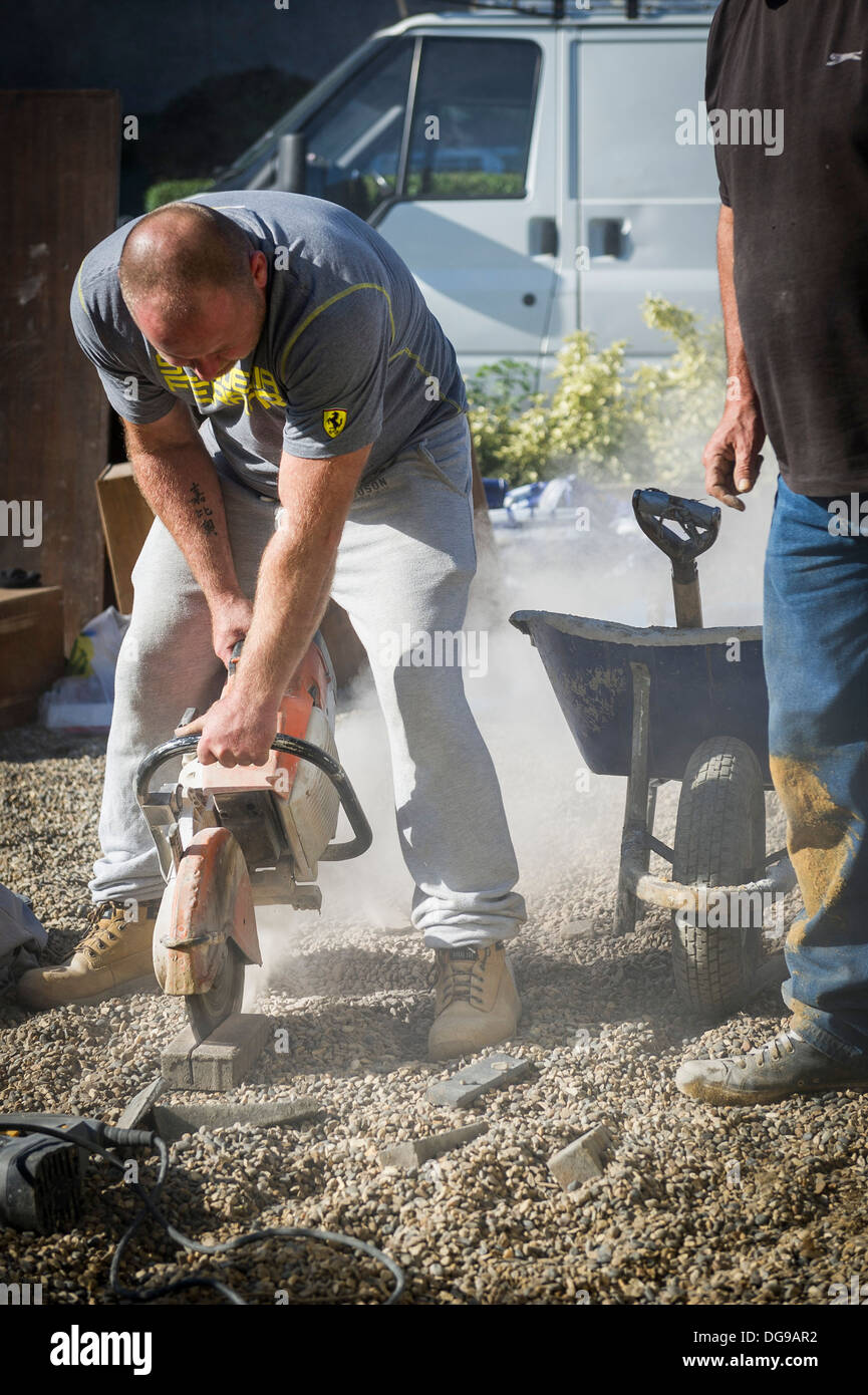 A worker using a disc cutter to cut a paving block Stock Photo - Alamy