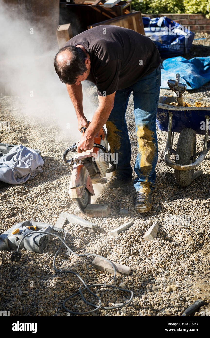 A worker using a disc cutter to cut a paving block Stock Photo - Alamy