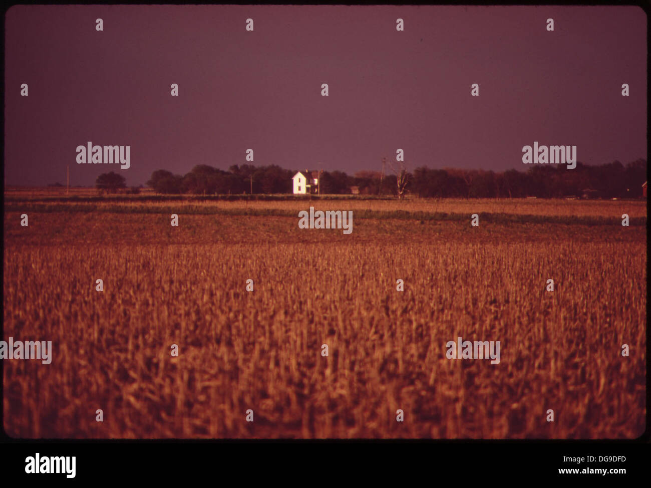 This photograph captures a farmhouse at dusk, with dark rain clouds ...