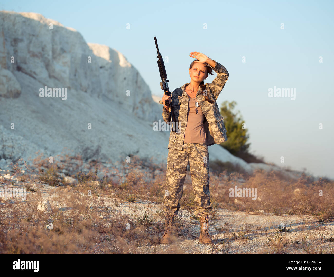 Young beautiful female soldier dressed in a camouflage with a gun in ...