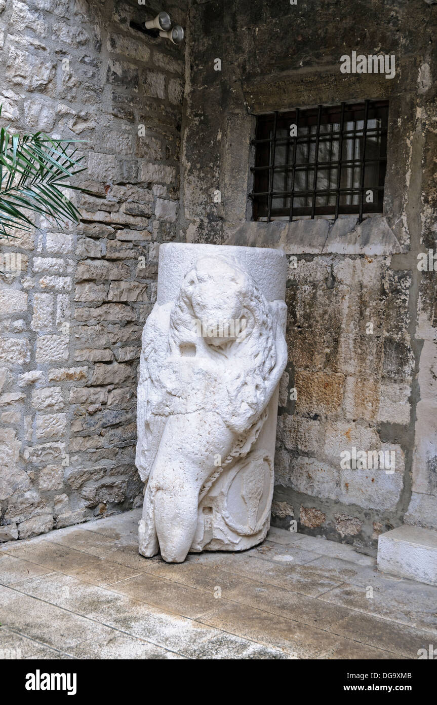 An eroded white stone statue stands by an entrance to the Gothic style ...
