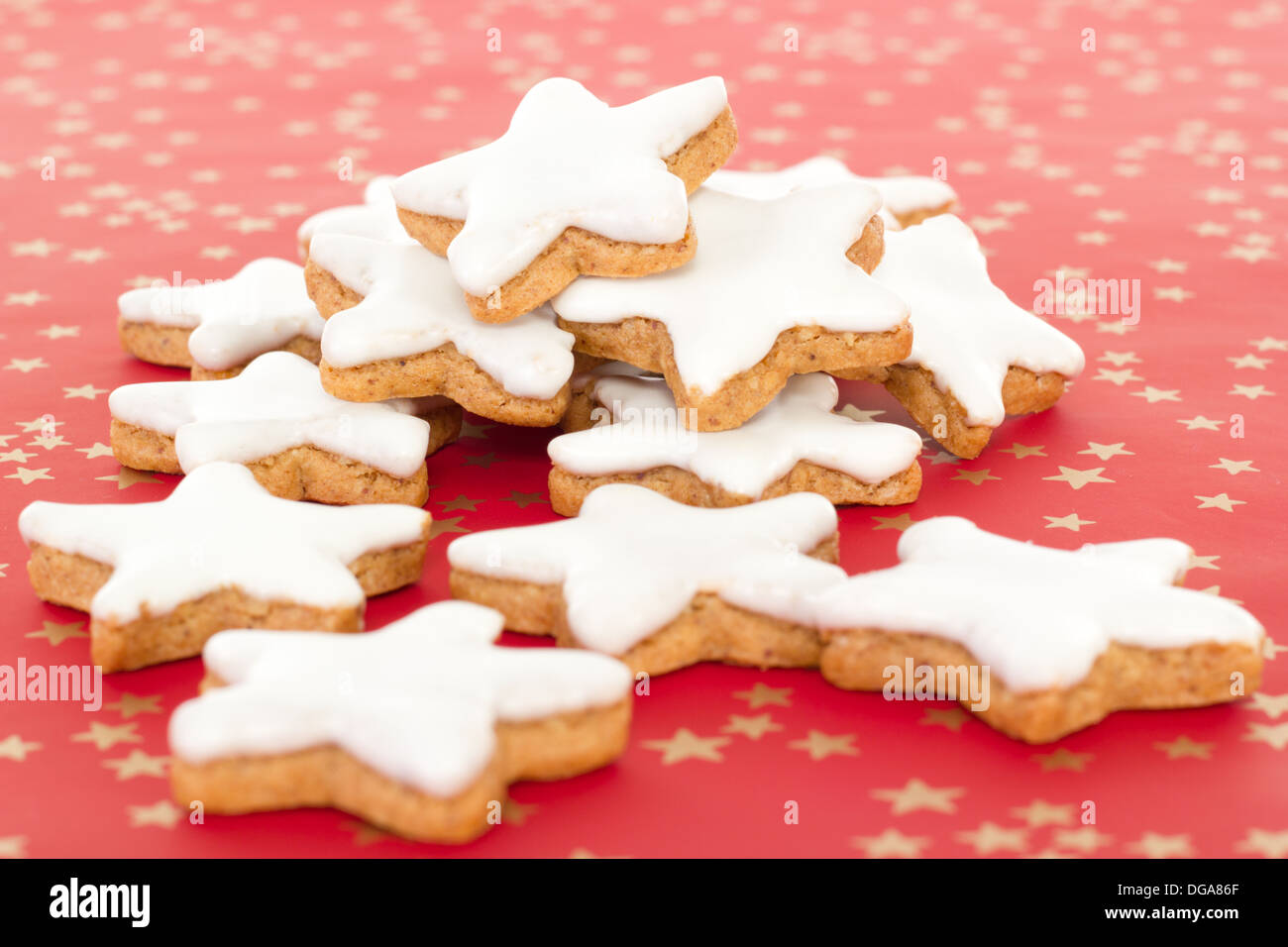 Many star shaped cinnamon biscuits on red background with golden stars ...