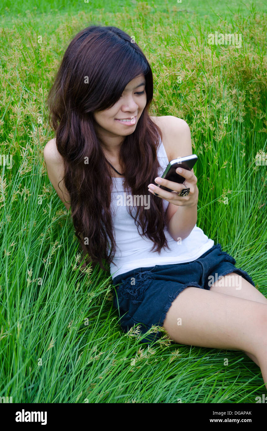 asian cute girl texting on meadow with happy face Stock Photo - Alamy