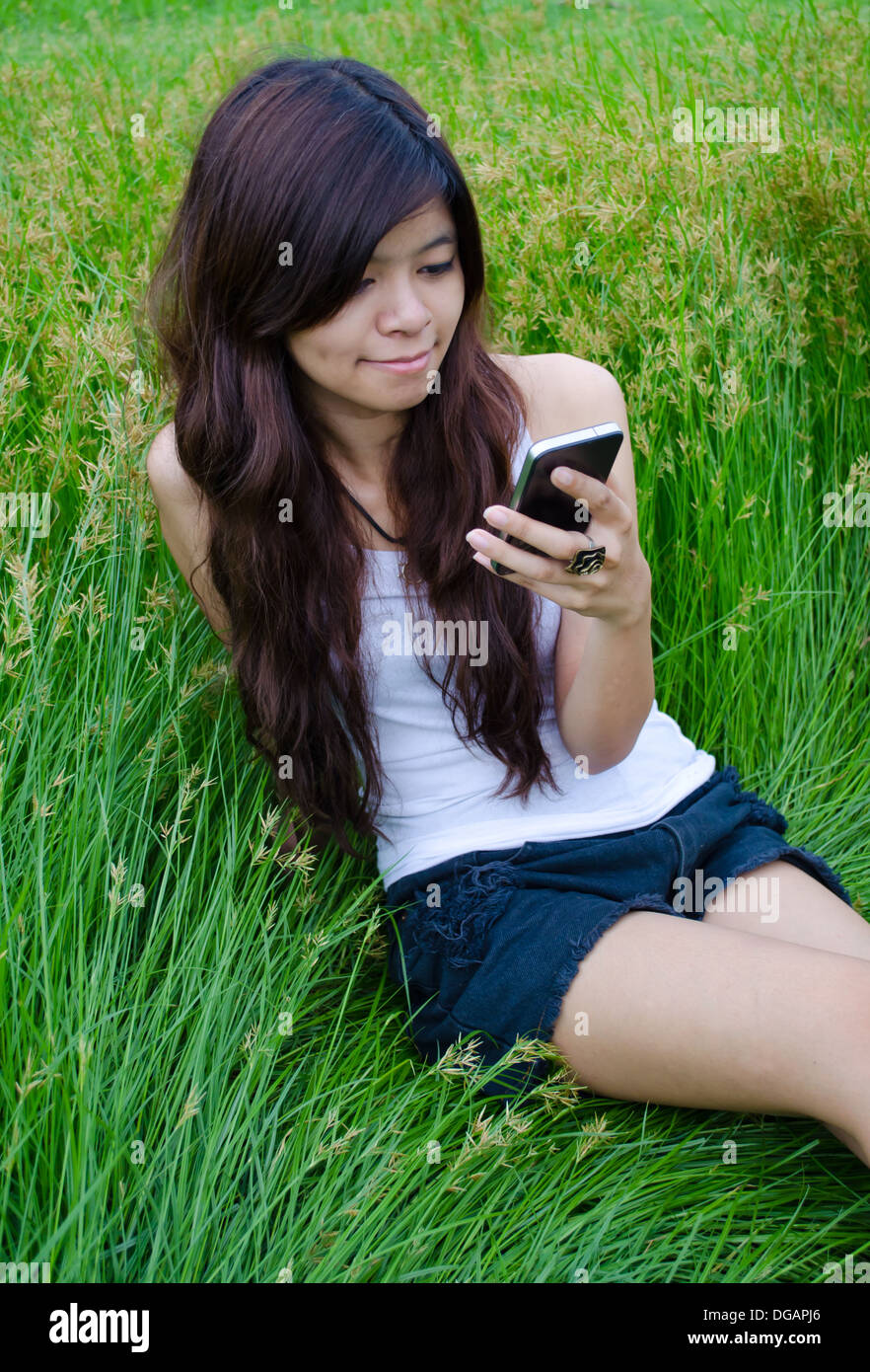 asian cute girl texting on meadow with happy face Stock Photo - Alamy