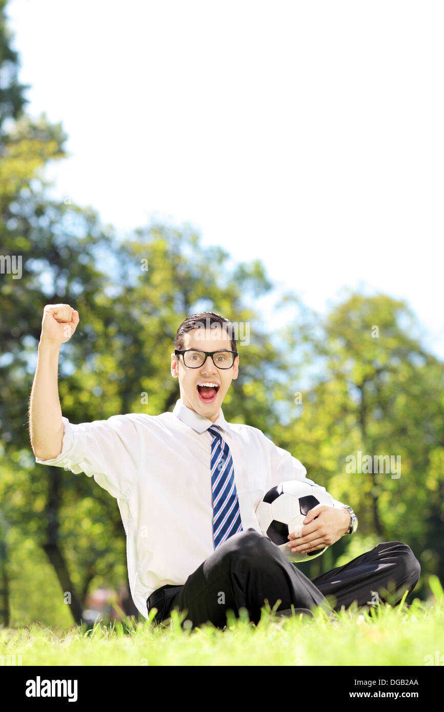 Young smiling man holding a ball and gesturing happiness in the park ...