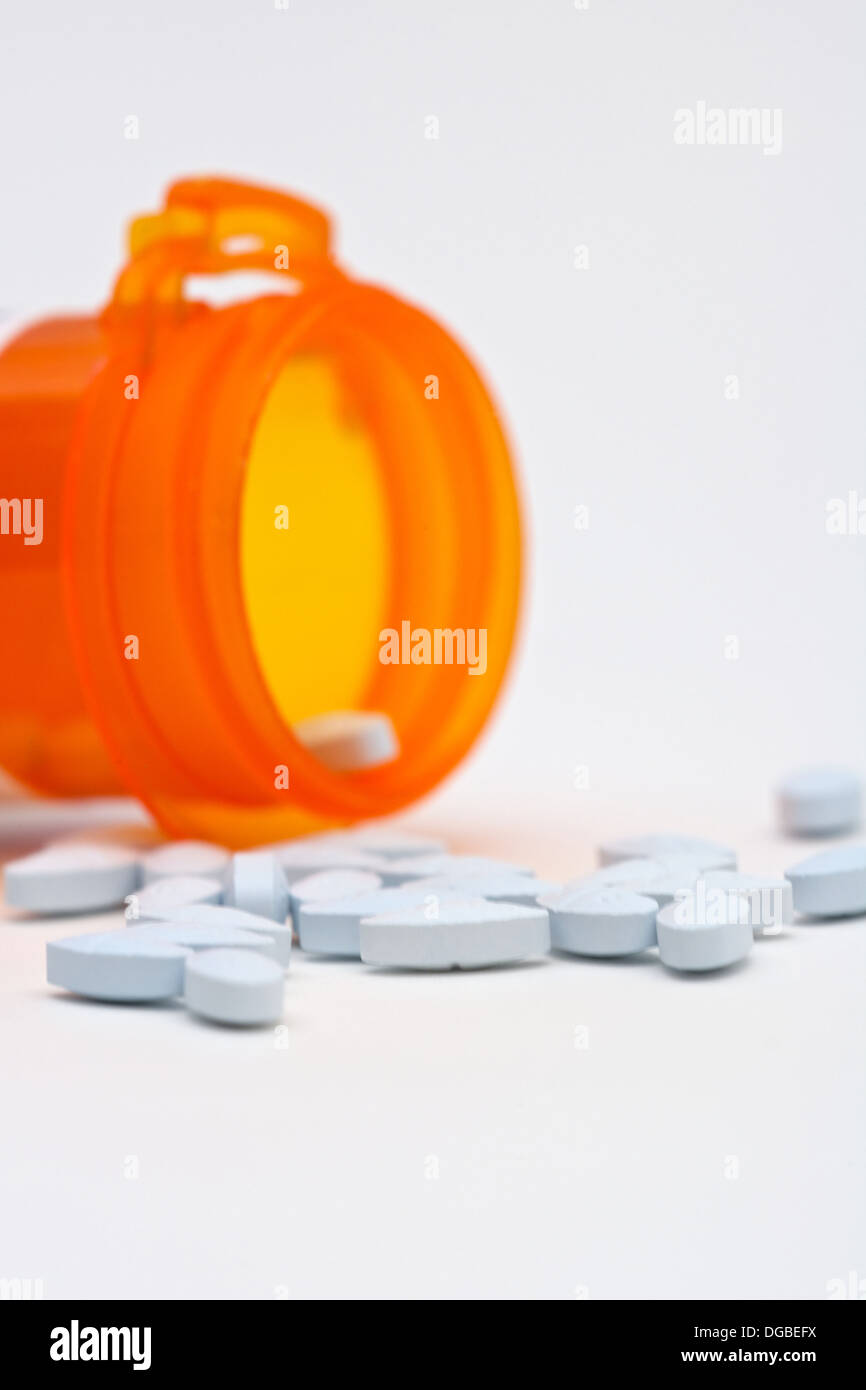 Pills and overturned pill bottles spilled out on a white background ...