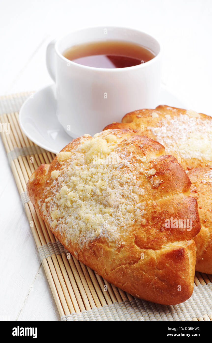 Two sweet buns and cup of tea on white table Stock Photo - Alamy