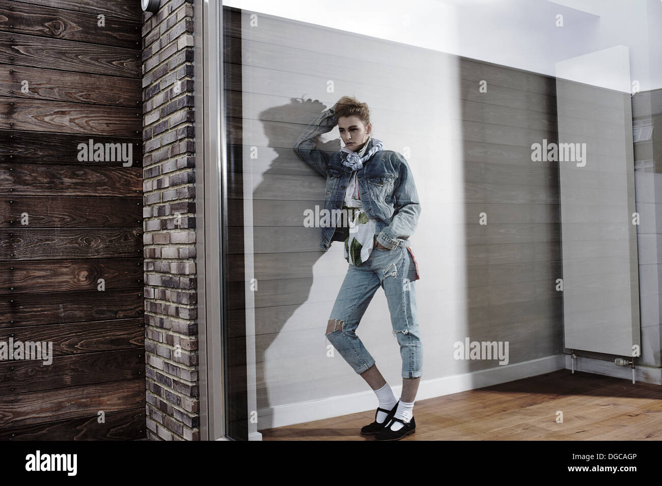Young woman leaning against wall looking out of window Stock Photo - Alamy
