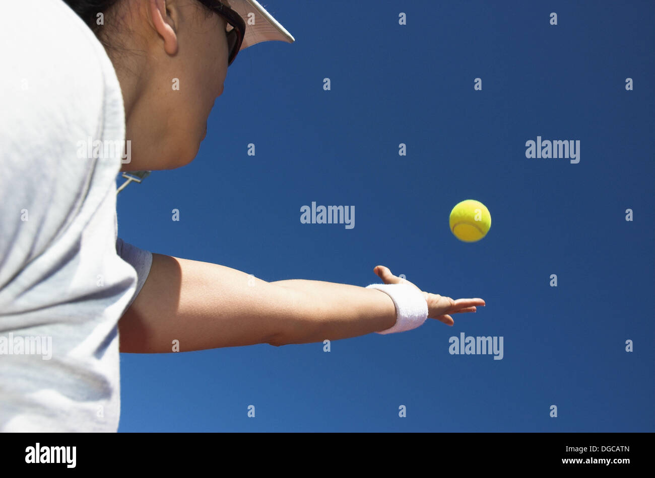 Female tennis player tosses ball into air to serve Stock Photo - Alamy