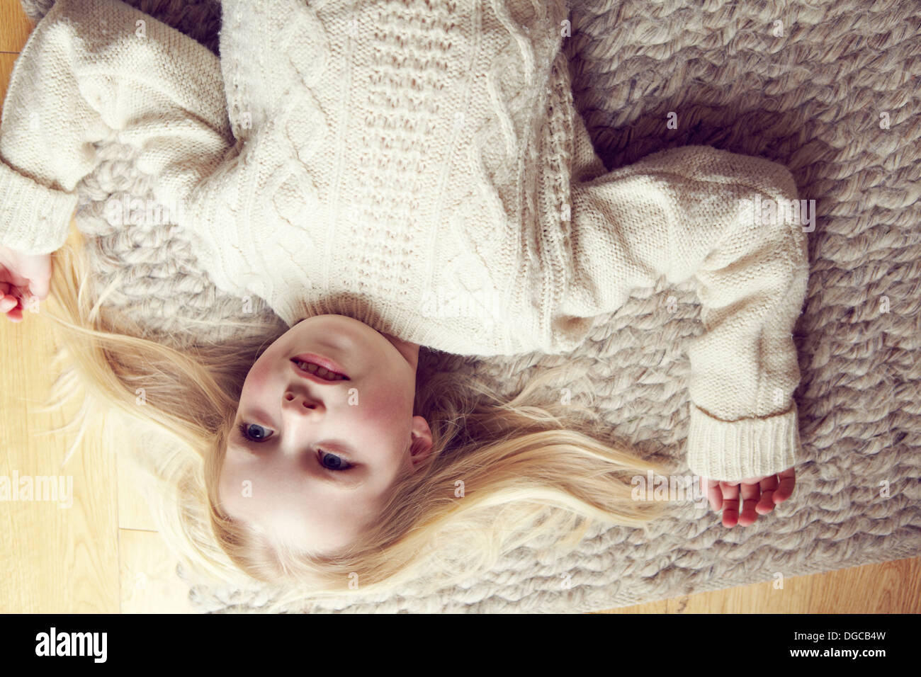 Young girl lying on rug Stock Photo - Alamy