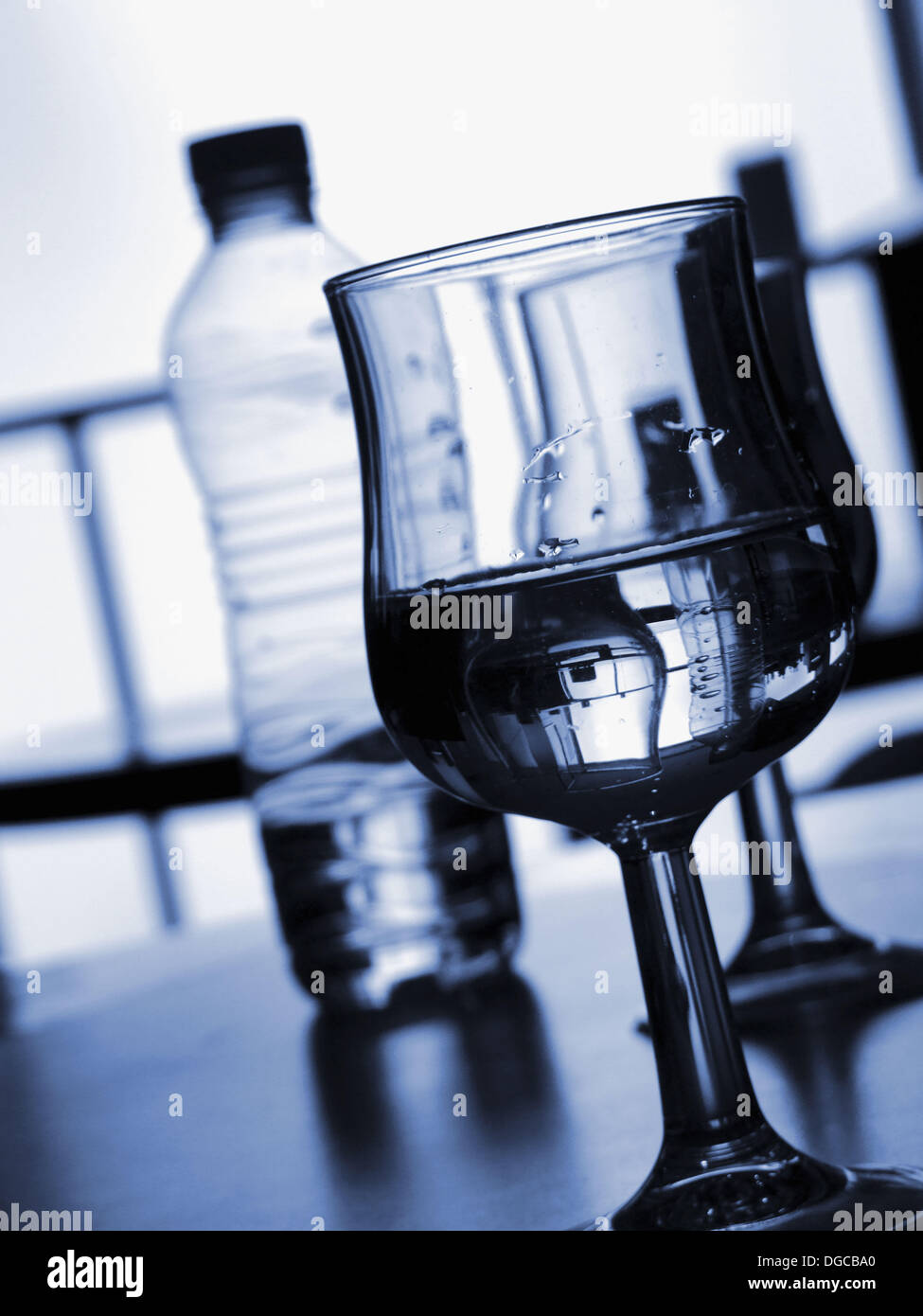 Inclined glass cup with a bottle of mineral water in the background out ...