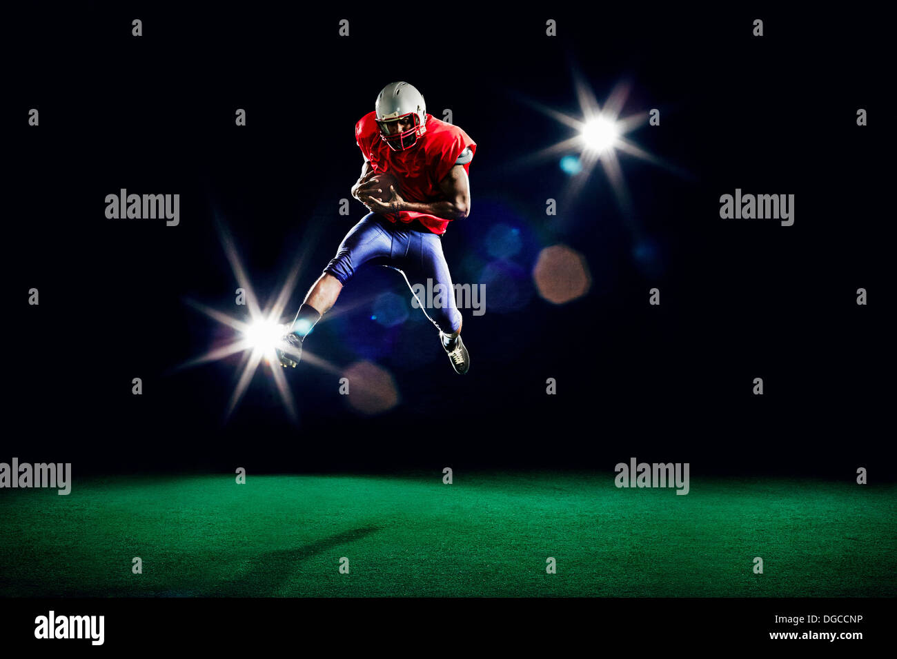 American football player mid air holding ball Stock Photo - Alamy