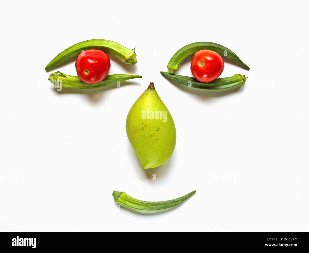 Lady finger, tomatos and a mango are arranged in human face like shape ...