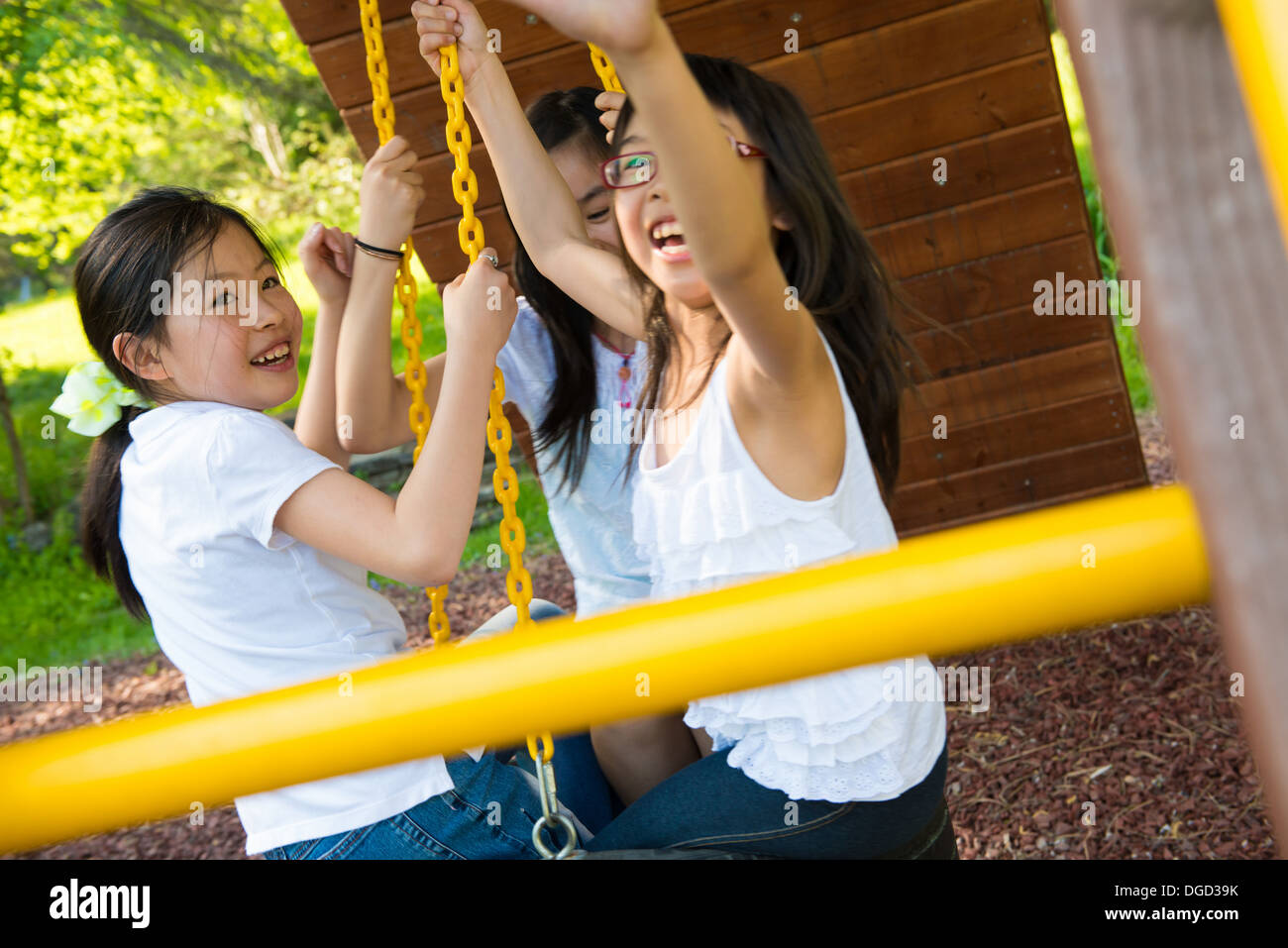 Three girls playing on swing Stock Photo - Alamy