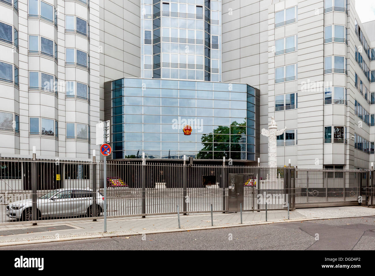 Fenced White concrete building, glass entrance and symbolic artworks of ...