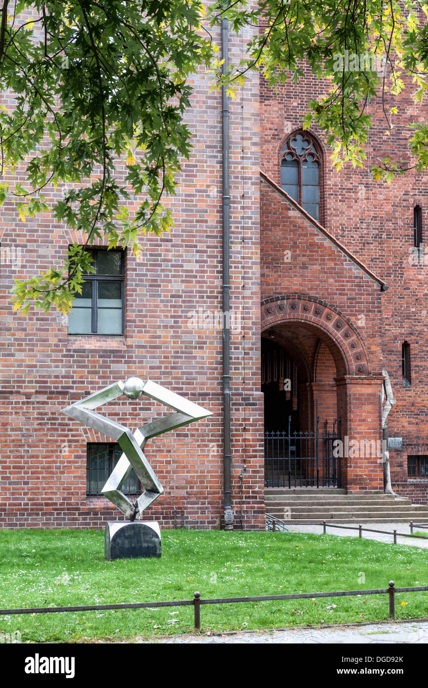 Modern sculpture at the entrance of the red brick Gothic-style building ...