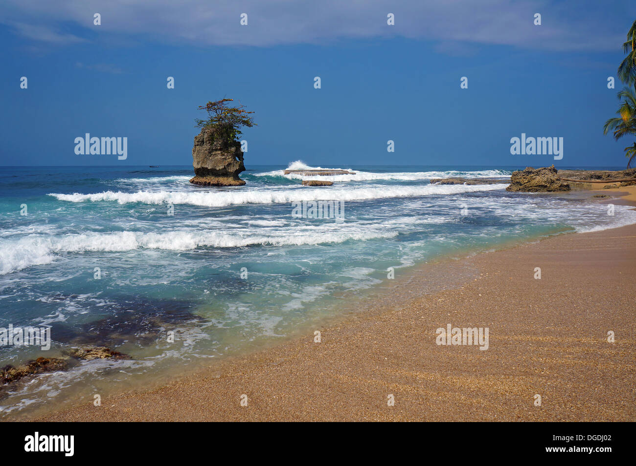 Sandy beach with rocky islet and waves breaking on the reef, Costa Rica ...