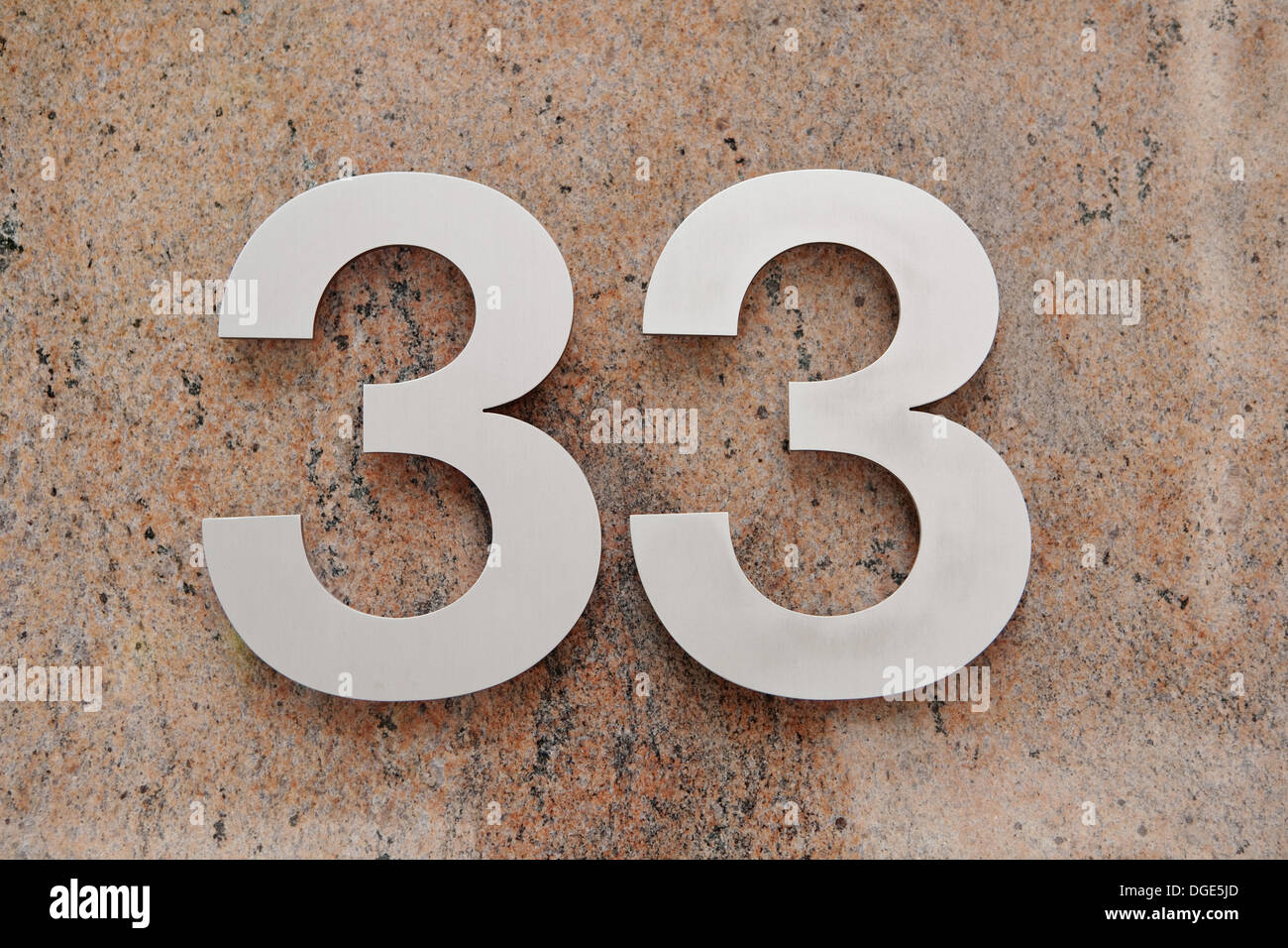 Number 33 against a pink marble wall Stock Photo - Alamy
