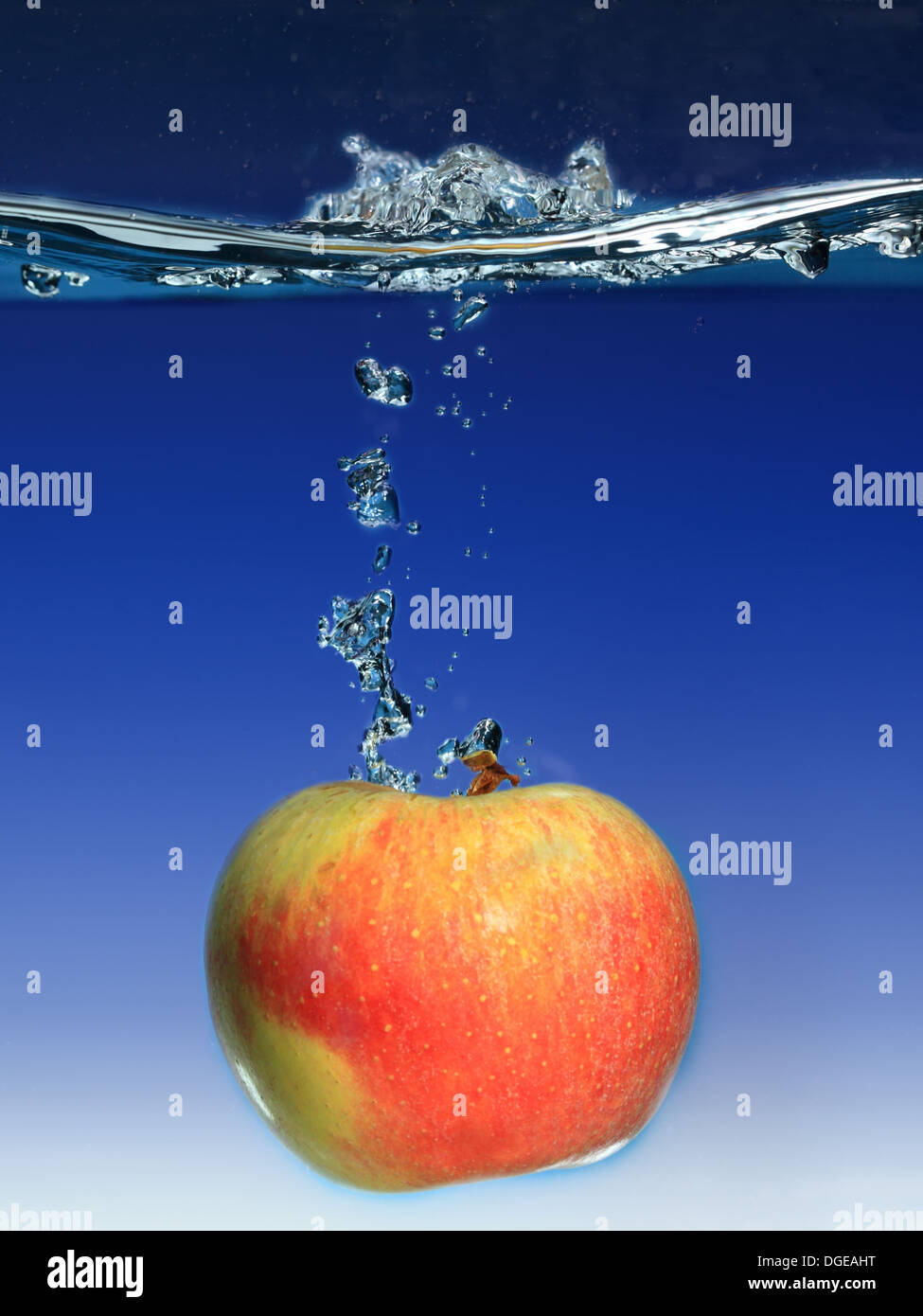 Yellow red apple in the water splash over blue background. Healthy food ...