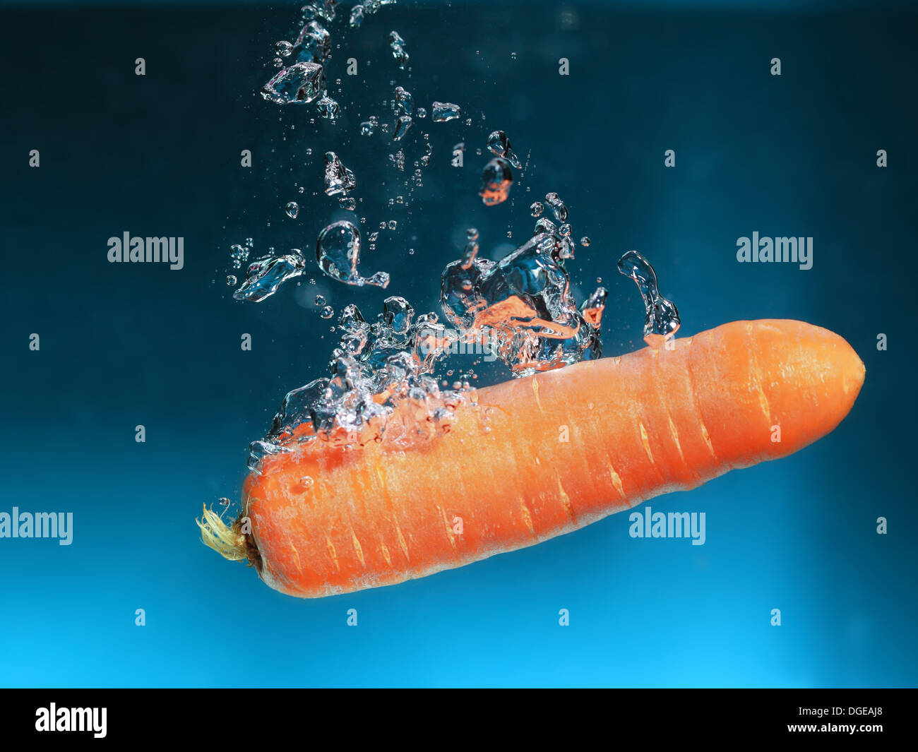 Carrot in the water splash over blue background. Healthy food and ...
