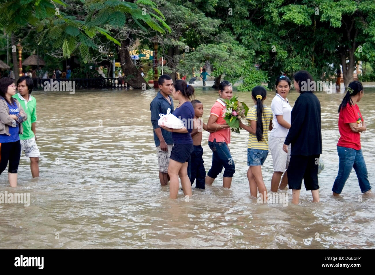 A group of people are wading in water on a flooded city street in Siem ...