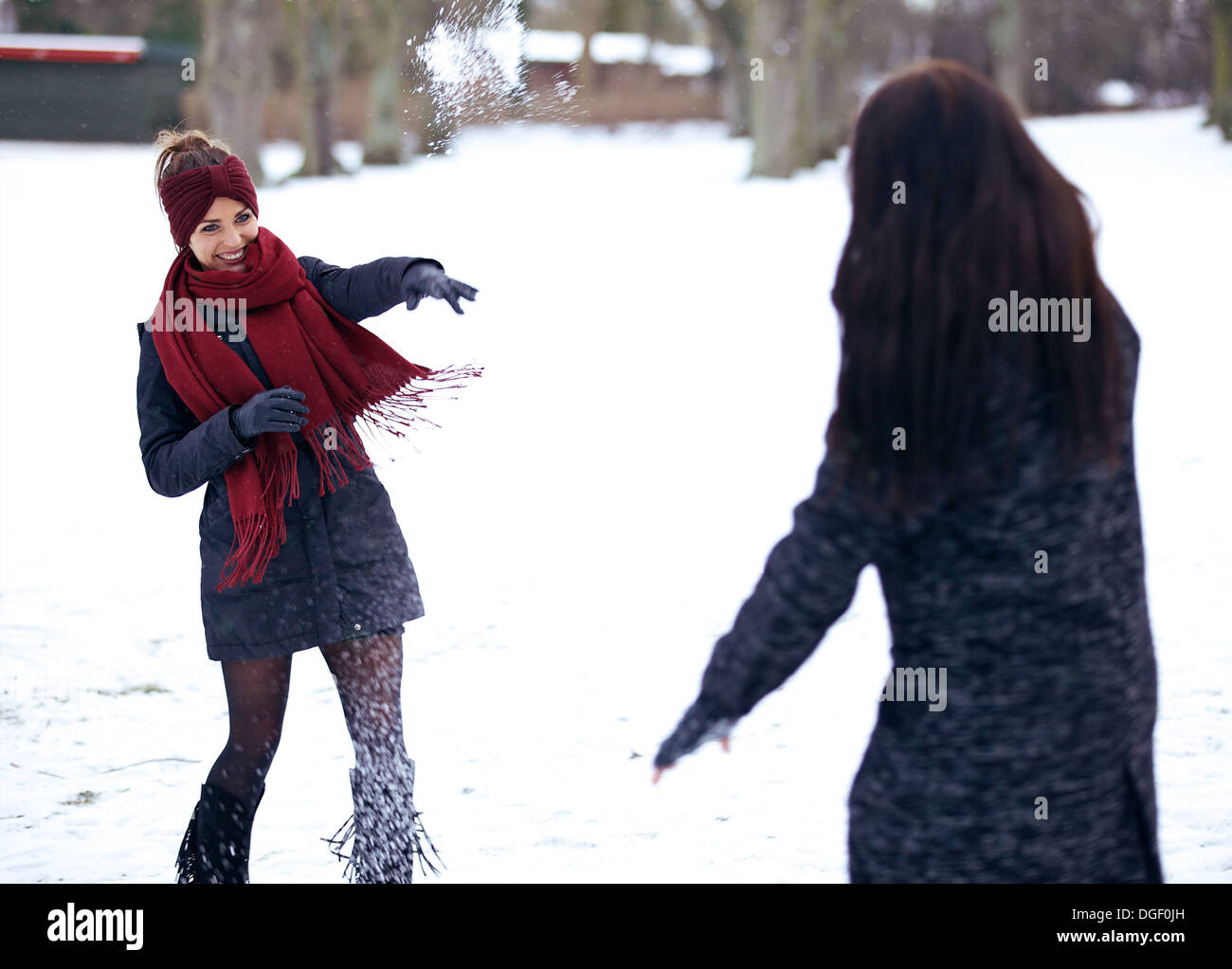 Playful women having fun and throwing snowballs at each other in a ...