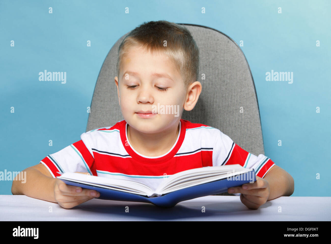 Young boy reading a book, child kid on blue background holding an open ...