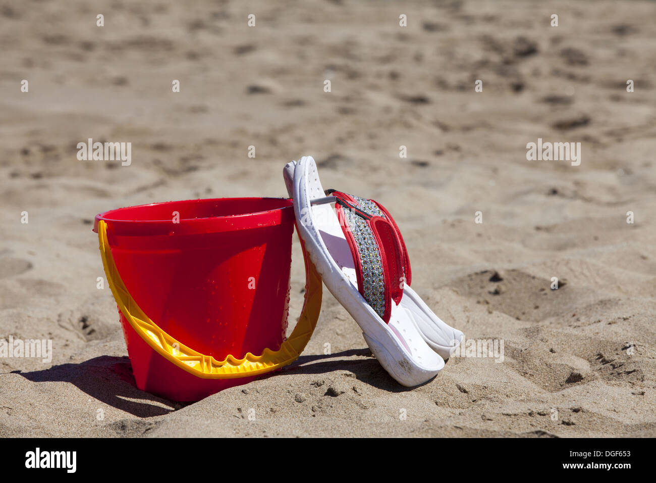 Flip-Flops and a red Beach Bucket on the Beach with Copy Space in upper ...