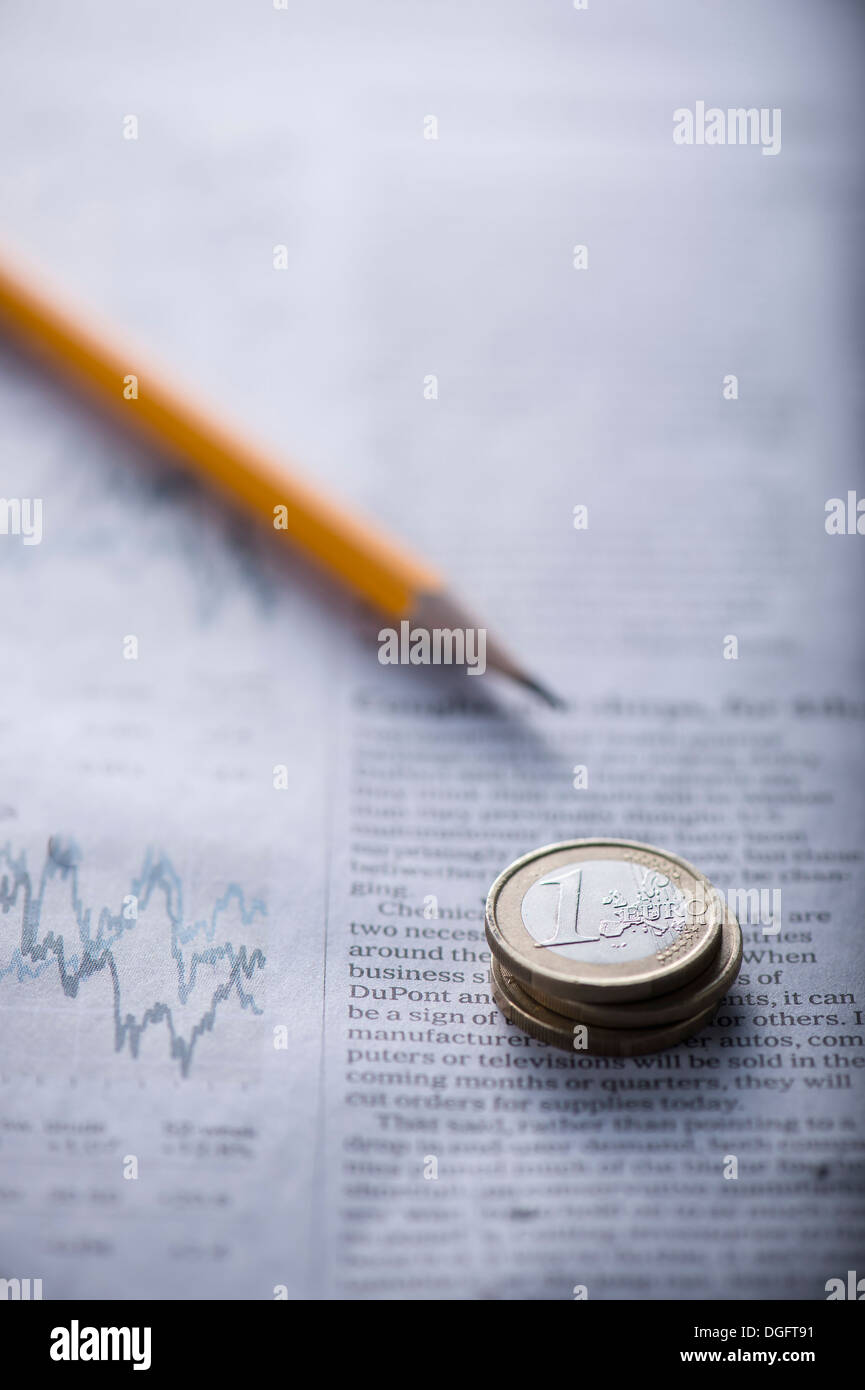 a pencil next to a pile of coins Stock Photo - Alamy