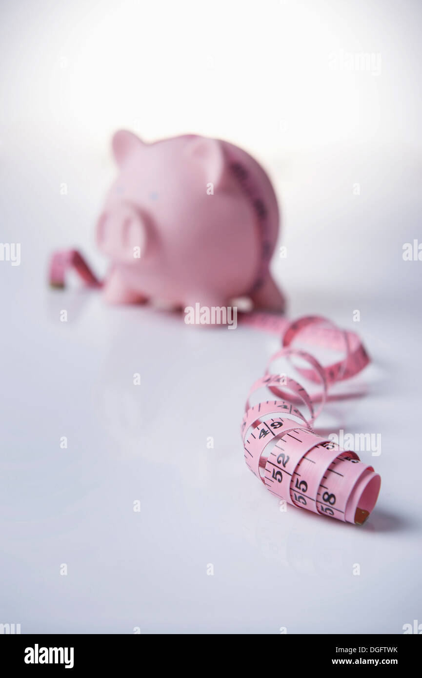 a pink piggy bank with a measurement band Stock Photo - Alamy
