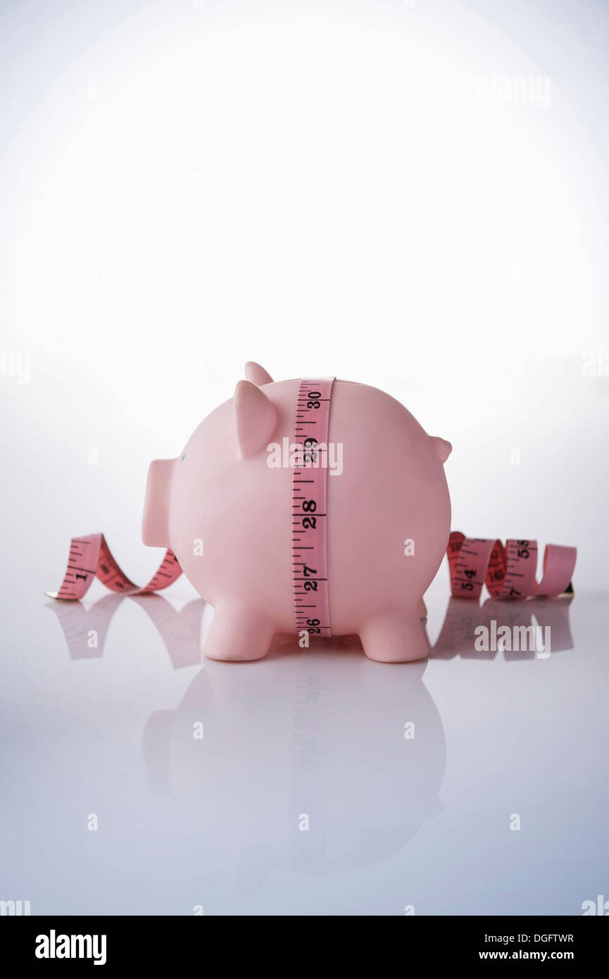 a pink piggy bank with a measurement band Stock Photo - Alamy