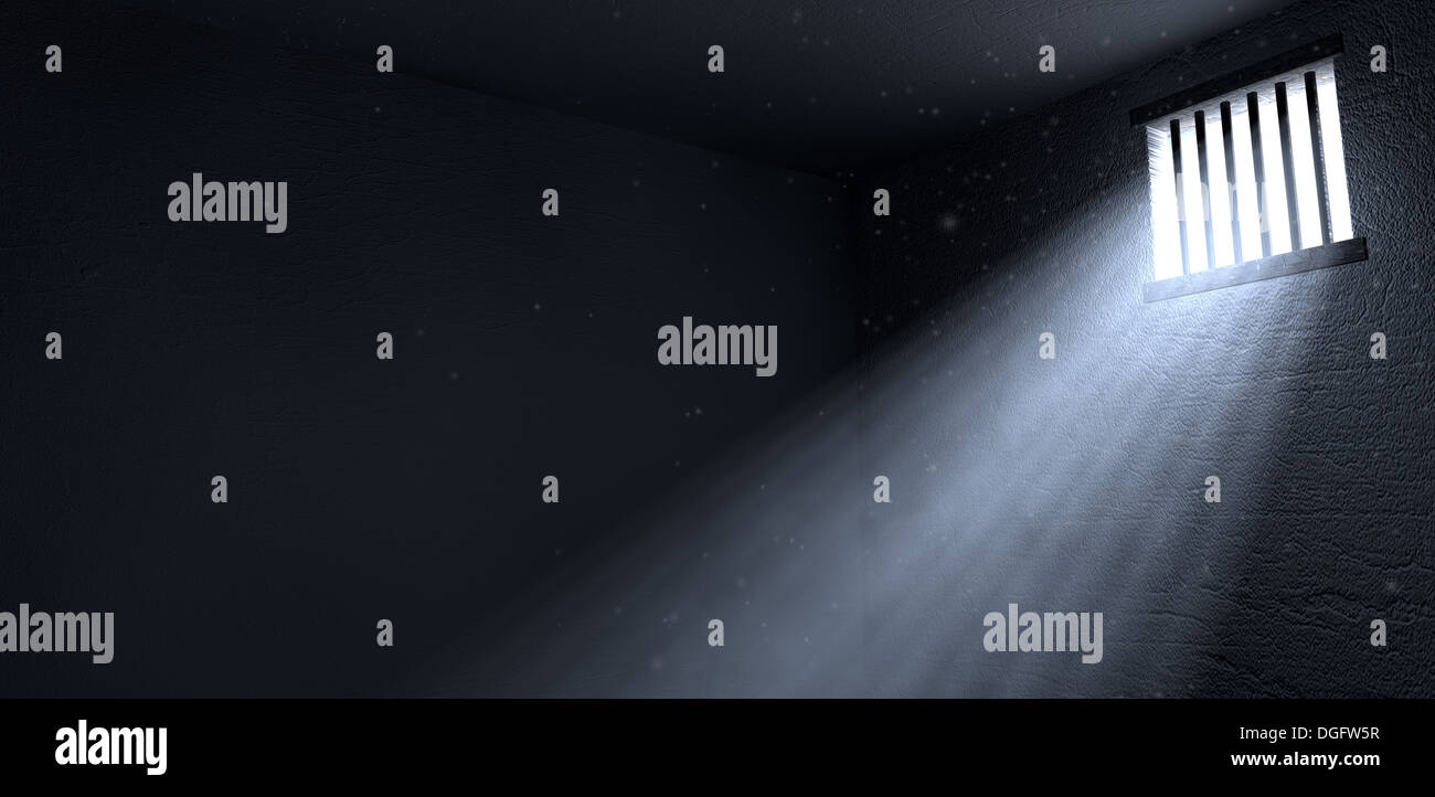 An old jail cell interior with barred up window with light rays penetrating through it ...