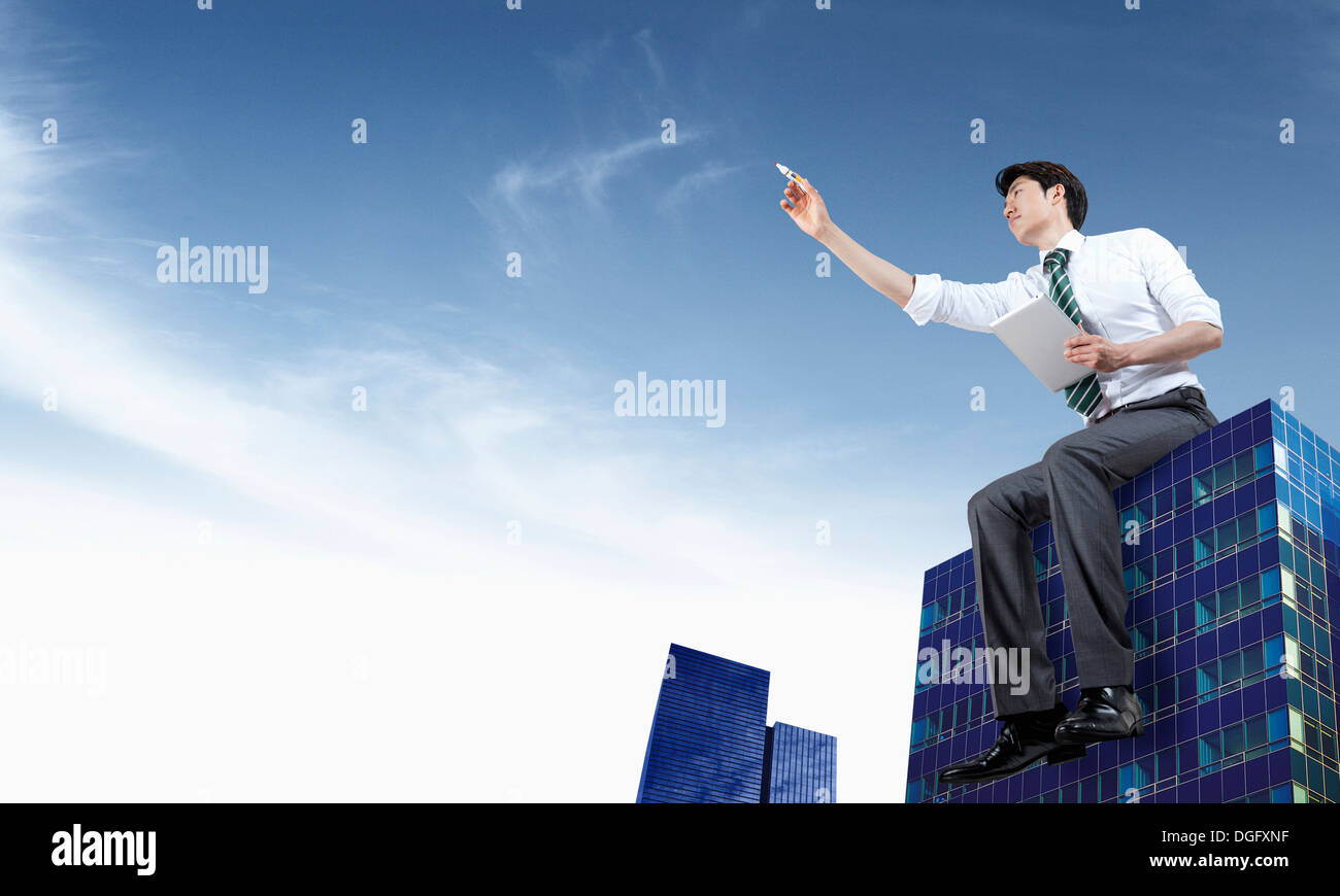a giant business man sitting on a building Stock Photo - Alamy