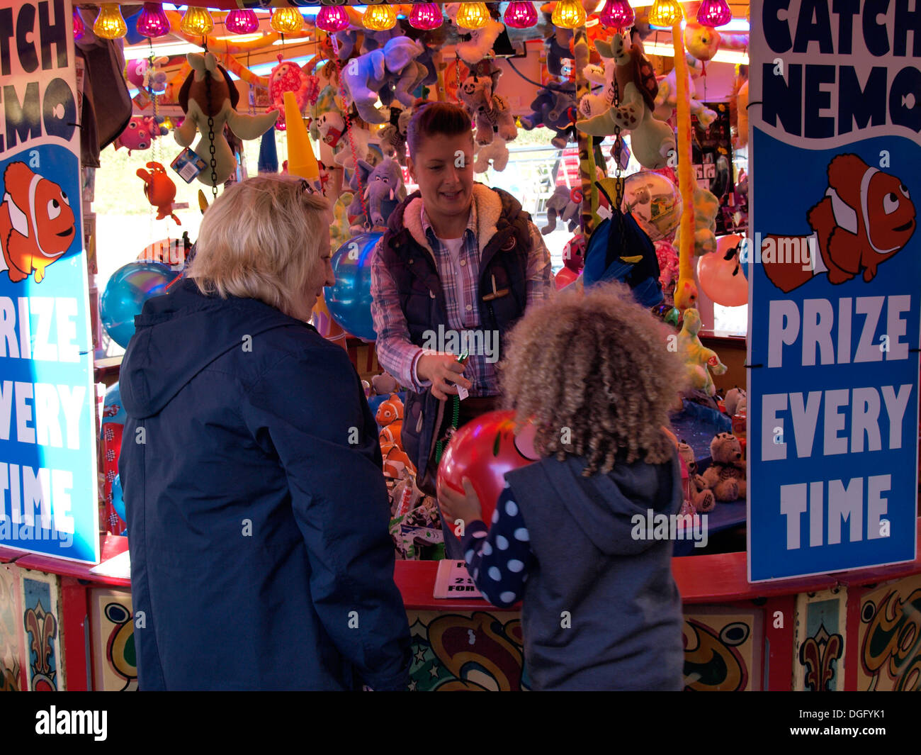 Child receiving prize from vendor of a hook a Nemo game stall at ...