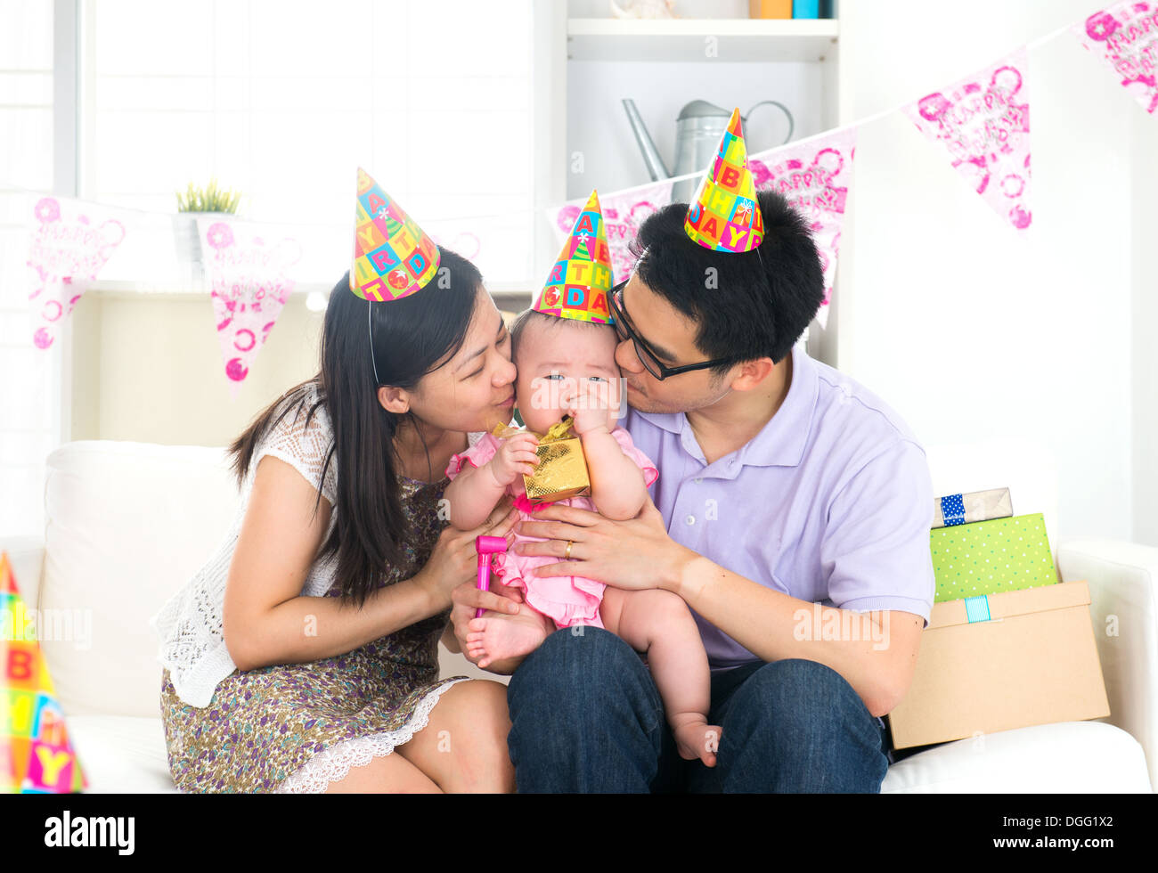 asian chinese parent kissing baby on birthday party Stock Photo - Alamy