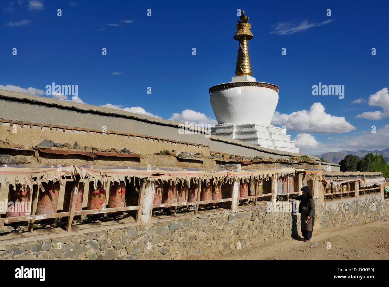 Tibetan pilgrim spinning prayer wheels outside the walls of Tashilhunpo ...