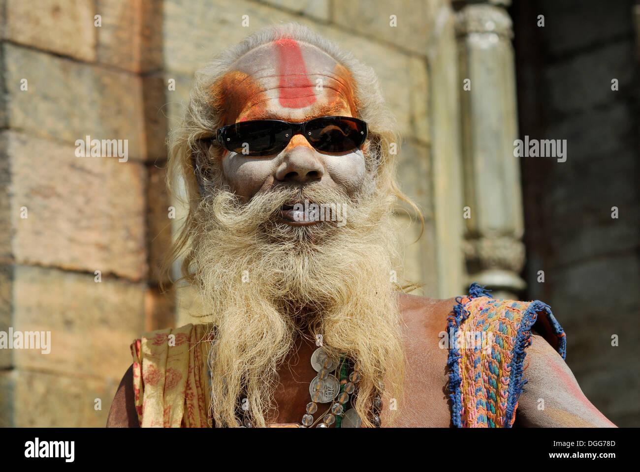 Holy man, Sadhu, with a painted face, a long beard and sunglasses ...