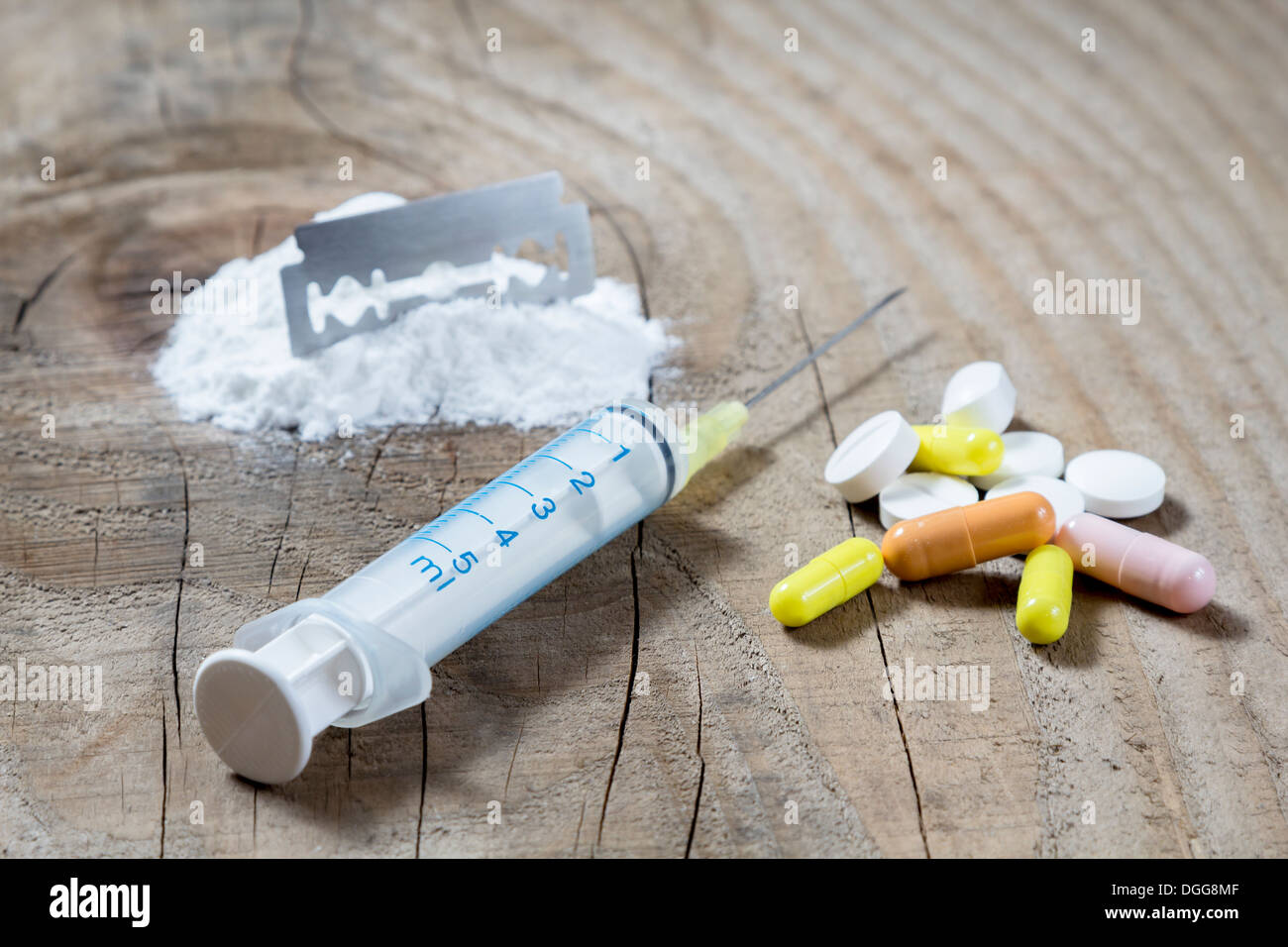 Heroin with razor blade, a single use syringe and different pills on a ...
