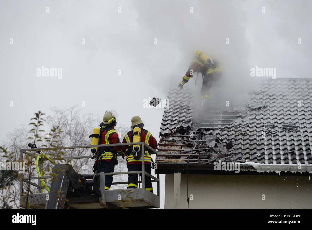 Firefighters wearing breathing equipment while extinguishing a roof ...