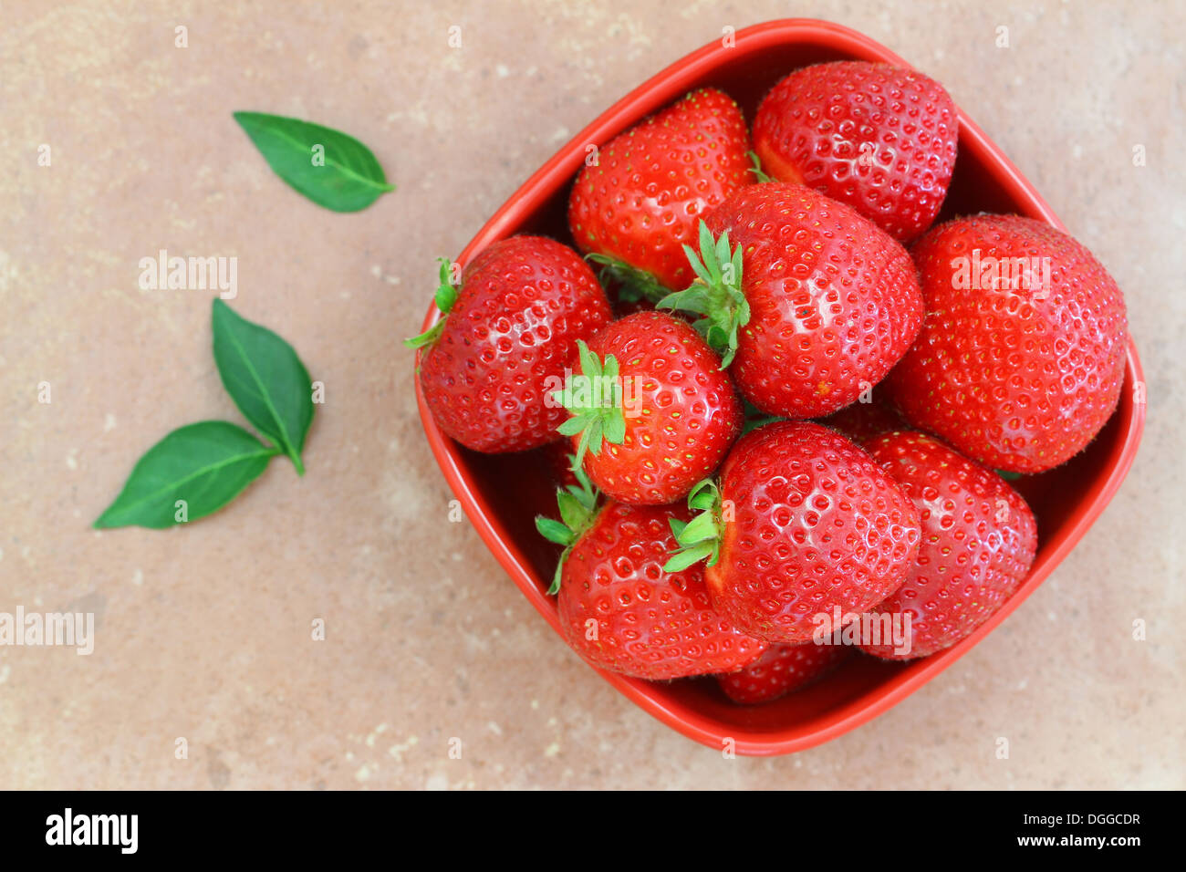 Strawberries in bowl on terracotta surface Stock Photo - Alamy