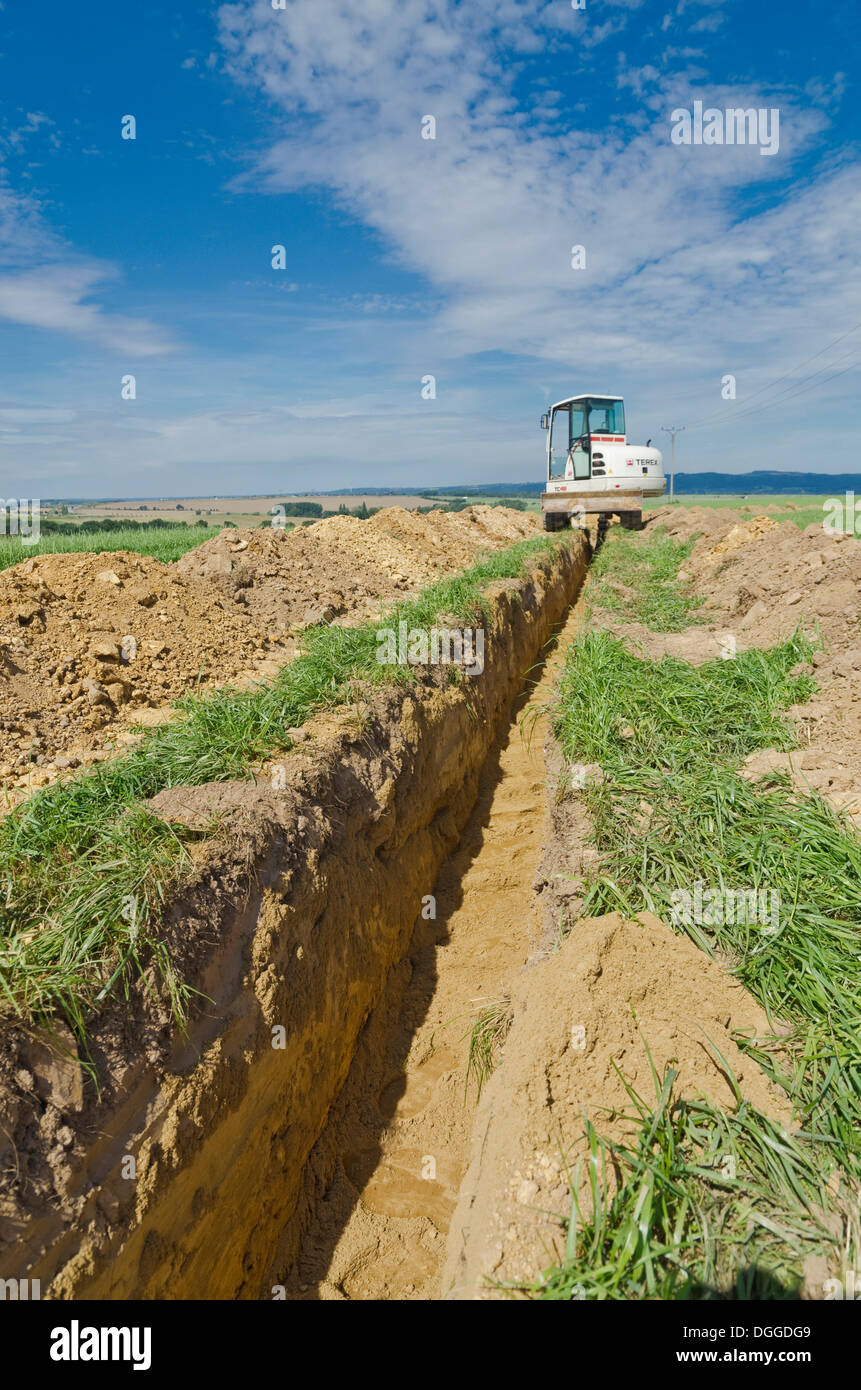 Excavator digging a channel through agriculture landscape, Laurich ...