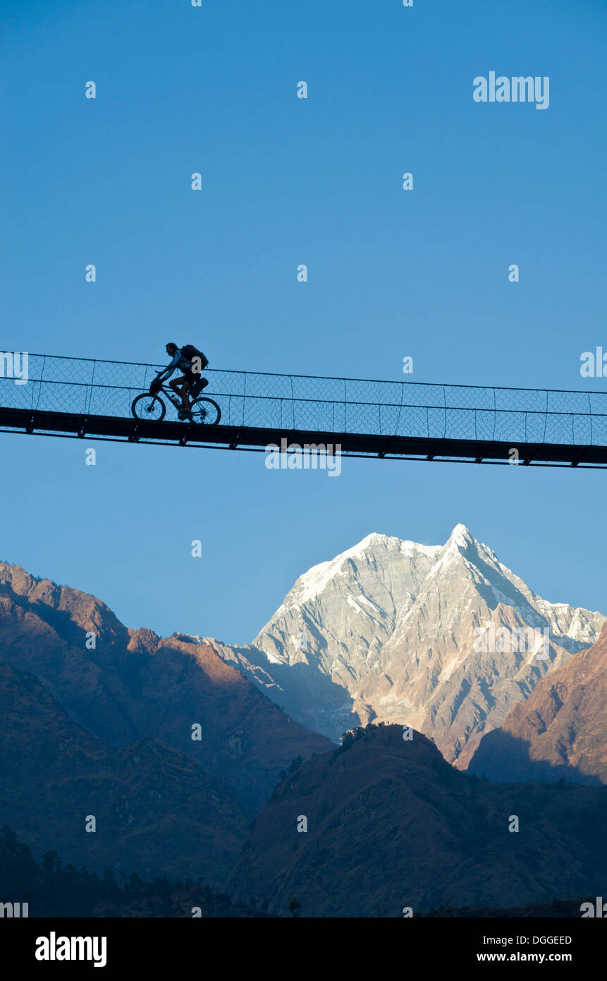 Cyclist crossing a suspension Bridge over Kali Ghandaki Valley, Nilgiri ...