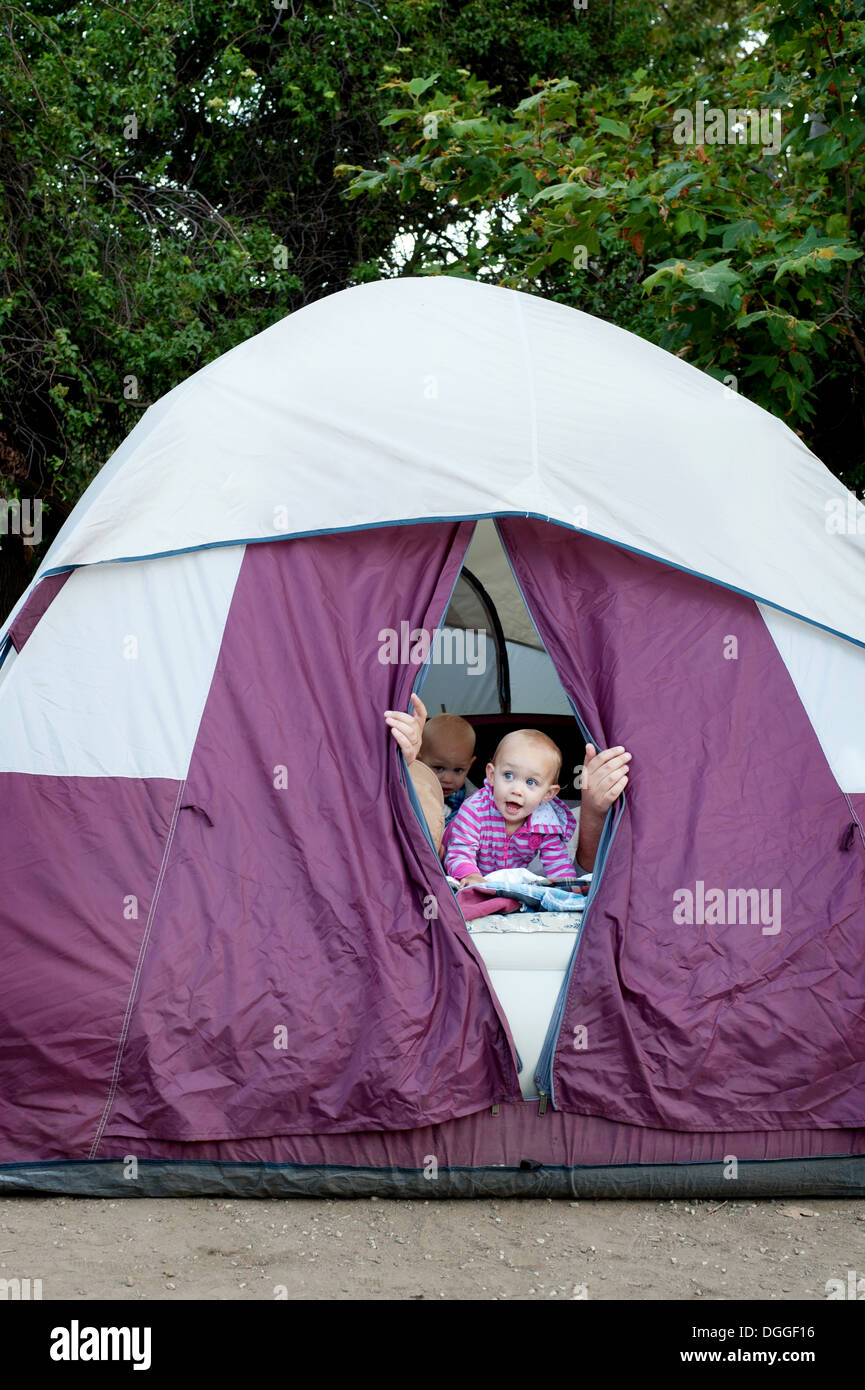 Toddler twins and father peeking out of tent Stock Photo - Alamy