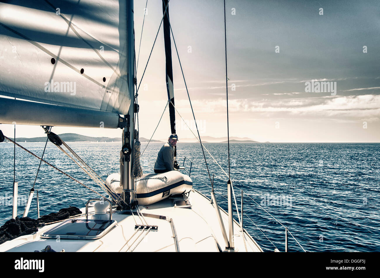 Skipper sitting at the bow of his sailing yacht looking towards aft ...