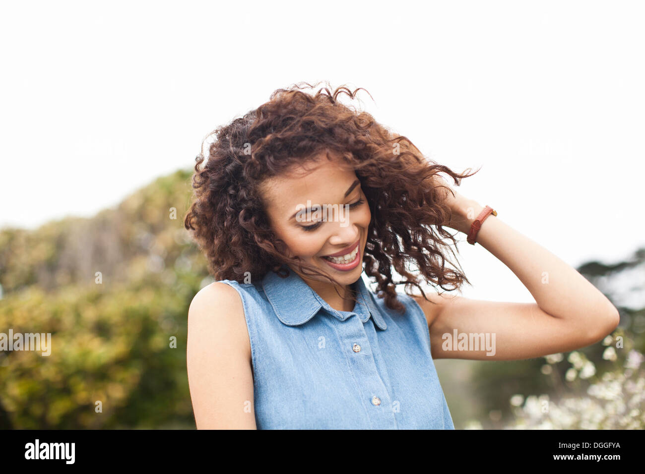Young woman with hand in hair, smiling Stock Photo - Alamy